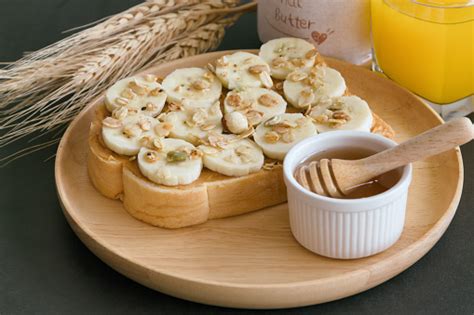 꿀 나무 접시에 바나나 땅콩 버터 토스트 샌드위치 홈메이드 오픈 샌드위치 바나나 슬라이스 및 그 라 놀라와 위에 땅콩 버터를