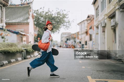 구시가지에서 스케이트보드를 들고 길을 건너는 행복한 아시아 중국 여성 아시아인에 대한 스톡 사진 및 기타 이미지 아시아인 걷기 Z세대 Istock