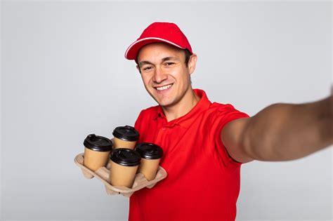 빨간 티셔츠와 모자에 배달 서비스에서 행복 한 남자 음식 주문을 주고 흰색 배경 위에 고립 된 커피 상자를 들고 T 셔츠에 대한 스톡 사진 및 기타 이미지 Istock