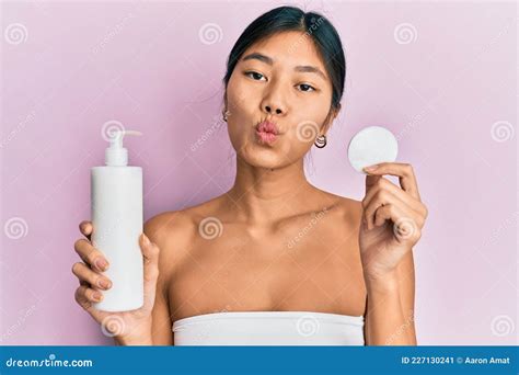 Young Chinese Woman Wearing Shower Towel Using Clean Lotion Looking At