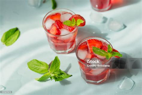 스파클링 와인과 여름 음료 샴페인 딸기 아이스 큐브 로즈마리를 블루 백그라운드에 담그거나 수제 상쾌한 과일 칵테일을 즐기세요