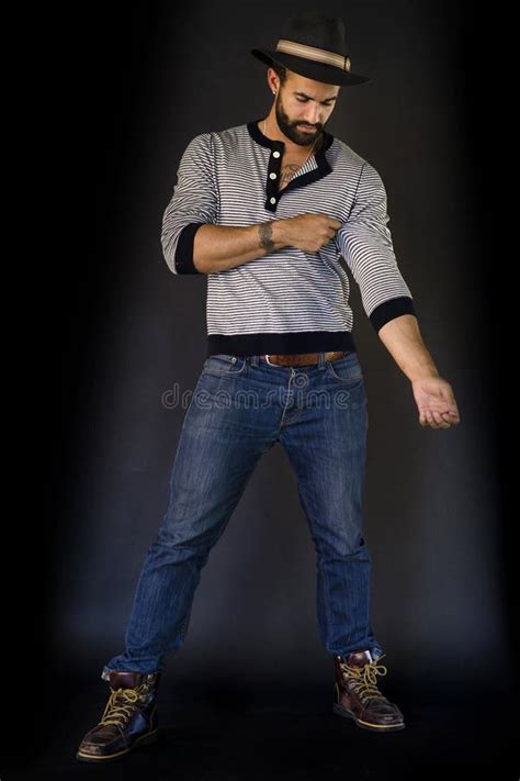 Молодой бородатый человек в шляпе джинсах рубашке и работниках Стоковое Изображение