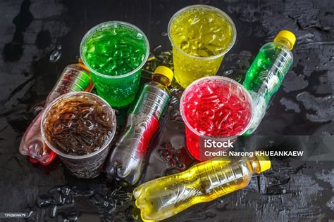 평면도 얼음 조각이 있는 화려하고 향긋한 플라스틱 잔에 담긴 많은 청량 음료 병 검은색 배경에 얼음 위에서 차갑게 얼음 위에 청량 음료 또는 탄산 음료 가득 찬에 대한 스톡