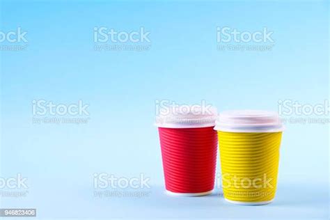 밝은 빨간색 및 노란색 이중의 쌍 벽으로 종이 컵 테이크아웃 커피가 게 모자 파란 배경에 승 뜨거운 음료에 대 한 두 개의 다채로운 환경 친화적인 열 증거 판지 머그잔을