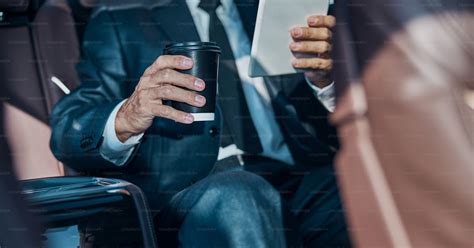 양복을 입은 우아한 남자의 자른 머리와 넥타이는 전송 중 뜨거운 음료와 터치패드 한 잔과 함께 뒤에 앉아 있다 사진 Unsplash의 비행 이미지