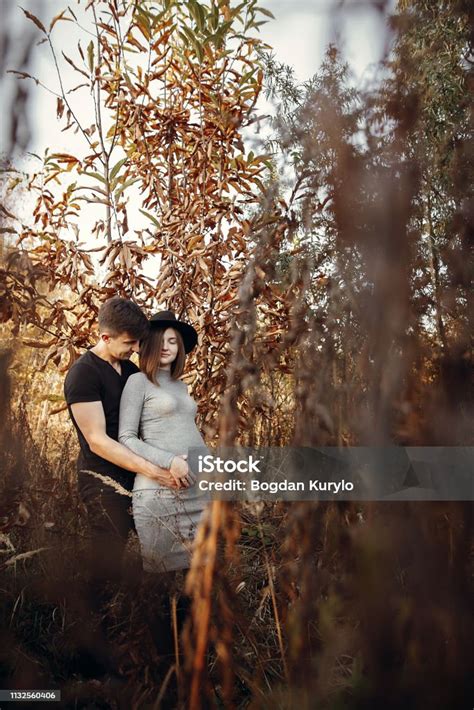 세련 된 임신한 커플가을 공원에서 화창한 빛에 배를 잡고 손을 들고 행복 한 젊은 부모 엄마와 아빠 아기 범프를 포옹 미소 일몰에 아름 다운 순간을 즐기고 부모의 개념