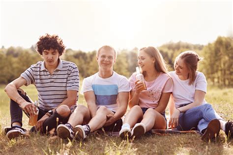 4 명의 긍정적인 친구 함께 기쁨을가지고 행복 한 식 푸른 잔디 야외에 앉아 여름 방학 동안 여가 시간을 즐길 자연에서 야외 포즈 사람 우정 및 레크리에이션의 개념 남자에