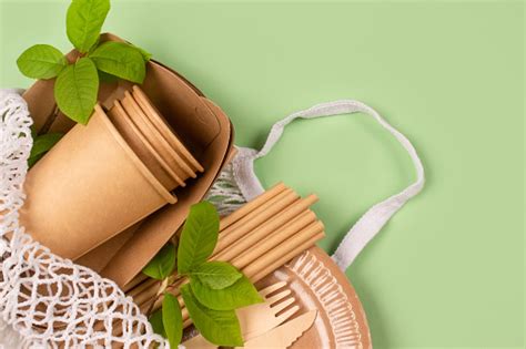 친환경 식기의 가까이 보기 복사 공간이있는 밝은 녹색 배경에 흰색 면 그물 가방에 나무 칼붙이와 크래프트 종이 식품 컵과 용기 길거리 식품 용지 포장 0명에 대한 스톡 사진