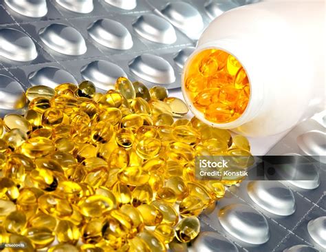 Yellow Liquid Capsules And Silvery Plates Of Medicines Near Bottle