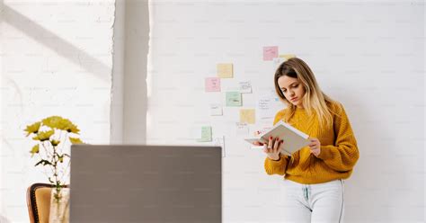 책을 들고 컴퓨터 앞에 서 있는 여성 사진 Unsplash의 계획 이미지