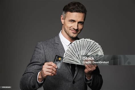 회색 배경에 고립 된 달러 지폐와 신용 카드로 상금을 보여주는 비즈니스 슈트에서 행운의 남자 30 대 사진 감독에 대한 스톡 사진 및 기타 이미지 Istock