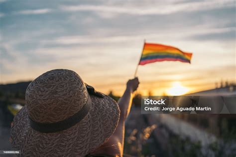 모자를 들고 하늘에 무지개 깃발을 흔드는 알아볼 수 없는 사람 Lgtbiq 컨셉 동맹에 대한 스톡 사진 및 기타 이미지 동맹