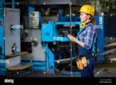 Side View Portrait Of Female Machine Operator Using Digital Tablet While Working With Power
