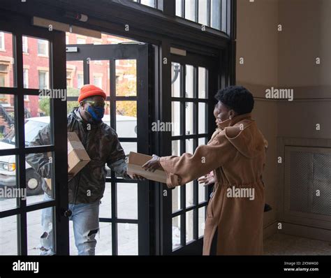 Mother Holding Daughter And Taking Package From Delivery Man Stock Photo Alamy