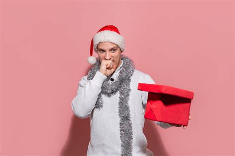 흰색 스웨터와 빨간 산타 모자를 입은 남자는 빨간 선물 상자에 무엇이 있는지 알고 싶어합니다 크리스마스와 새해 선물 겨울에 대한 스톡 사진 및 기타 이미지 Istock