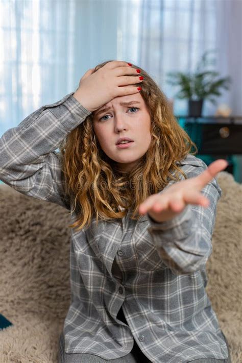 Woman Sits On Sofa Making Facepalm Gesture Feeling Disappointed