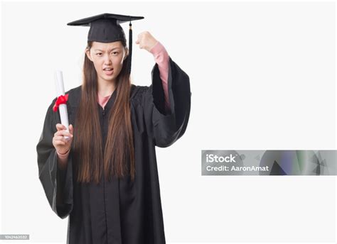 종이 들고 대학원 유니폼을 입고 젊은 중국 여자 화가 좌절된 소리와 분노 미친 개념 분노 제기 손으로 함 갈색 머리에 대한 스톡