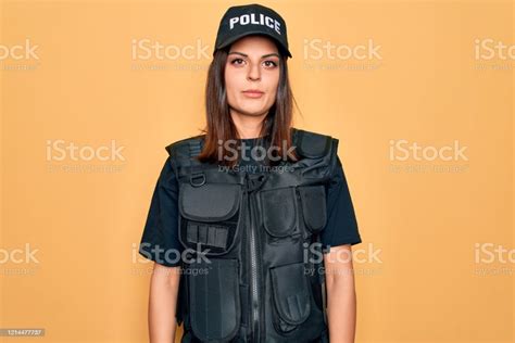 젊은 아름 다운 갈색 머리 경찰 을 입고 경찰 유니폼 방탄 및 모자 얼굴에 심각한 표정으로 편안 하 게 카메라를 보는 간단하고 자연스러운 경찰관에 대한 스톡 사진 및 기타