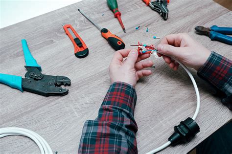 남성 전기 기술자가 전선의 플러그를 바꿉니다 전기 공구 작업 스트리퍼 크림프 스크루 드라이버 와이어 커터 전선을 연결하는 전기 기술자 전기 연료 및 전력 생산에 대한 스톡