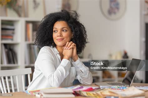 측면을 바라보는 젊은 아프리카 계 미국인 여성의 초상화 흰색 블라우스를 입은 여성 디자이너가 디자인 프로젝트를 위해 컬러 팔레트와 패브릭 샘플 근처의 사무실 테이블에 앉아