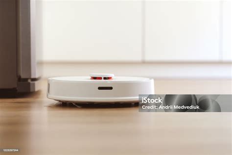 백색 로봇 진공 청소기는 이물질에서 바닥을 청소하고 전기 진공 청소기 진공 청소기 전기 로봇 청소 기술 로봇 진공 청소기의 상단보기로 집 청소하십시오 가구에 대한 스톡 사진