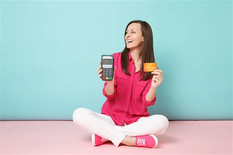 전체 길이 장미 셔츠에서 여자의 초상화 바닥에 앉아 흰 바지 잡고 밝은 핑크 블루 파스텔 벽 배경 스튜디오에 고립 된 터미널 카드 패션 라이프 스타일 개념입니다 복사 공간을