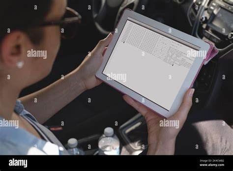 Biracial Female Programmer Sitting In Car Using Tablet With Coding On Screen Coding