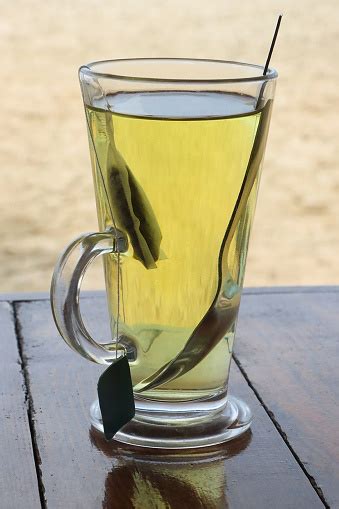 모래 사장을 바라보는 레스토랑 발코니 테이블에 티백과 금속 숟가락을 가진 녹차의 유리 머그잔의 클로즈업 이미지 전경에 초점 0명에 대한 스톡 사진 및 기타 이미지 Istock