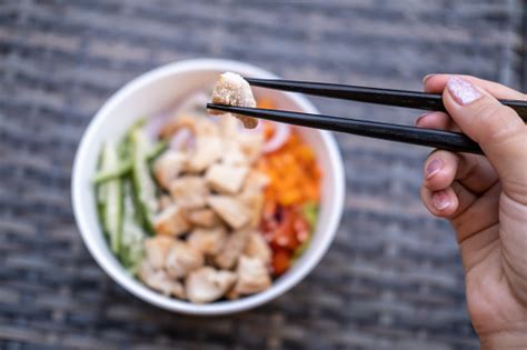 젓가락과 오이 쌀 당근 양파를 나무 테이블에 그릇에 담아 건강한 유기농 치킨 포크 그릇으로 손을 닫습니다 건강한 라이프스타일 건강한 식생활에 대한 스톡 사진 및 기타 이미지