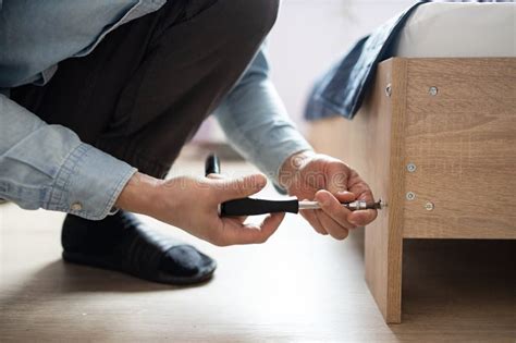 Man S Hands Assembling A Wooden Bed Using A Hexagon To Insert Screws
