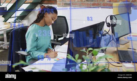 Image Of Statistical Data Processing Against African American Woman Taking Notes At Office Stock