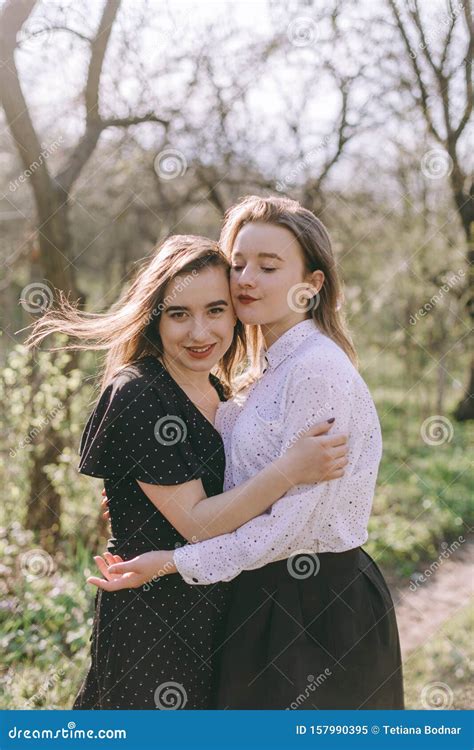 Portrait Of Two Beautiful Young Sisters In The Green Spring Garden