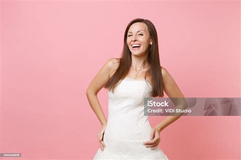 우아한 하얀 웨딩 레이스 드레스 핑크 파스텔 배경에 고립 된 두 팔으로 서 행복 한 신부 여자 웃음의 초상화 결혼식 축 하 개념입니다 광고에 대 한 공간을 복사 합니다 갈색