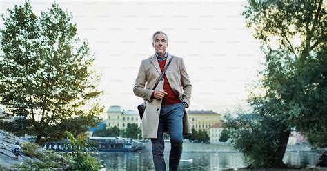 성숙한 잘 생긴 사업가 프라하의 도시에서 블 타바 강을 걷고 그 앞에 비둘기 무리 복사 공간 사진 Unsplash의 남자 이미지