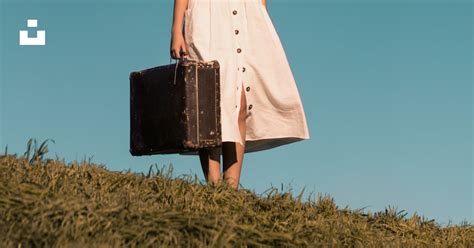 흰색 버튼 업 드레스를 입고 갈색 가죽 가방을 들고 푸른 풀밭에 서 있는 여자 사진 Unsplash의 무료 사람 이미지