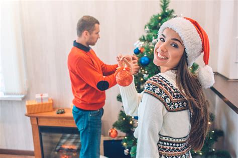 매력적인 젊은 여성이 서 있고 카메라에 좋은 그림 그녀는 웃는 다 크리스마스 트리를 장식 하는 남자 그는 집중입니다 크리스마스에 대한 스톡 사진 및 기타 이미지 Istock