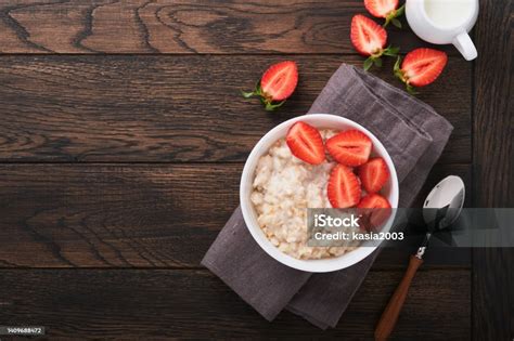 오트밀 오래된 나무 어두운 테이블 배경에 딸기 아몬드 및 우유가있는 오트밀 죽 그릇 평면 누워 스타일의 상단보기 천연 성분