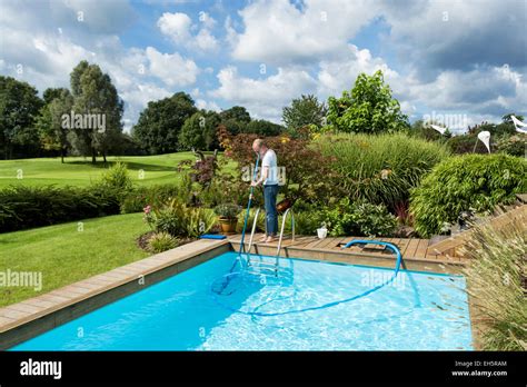 Full Length Of Man Cleaning Swimming Pool Using Telescopic Pole Stock Photo Alamy
