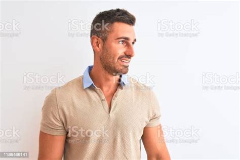 우아한 티셔츠를 입은 젊은 잘생긴 남자는 얼굴에 미소와 함께 옆으로 찾고 고립 된 배경에 자연스러운 표정 자신감 있게 웃고