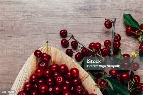 나무 테이블에 나무 접시에 신선한 빨간 체리 나무 접시 그것에 나무 Backgroundnext에 체리와 녹색 잎 벚꽃 지점 이다 삼각형의 형태로 접시입니다 생태학입니다 적절