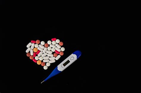 많은 다른 알 약과 정제 검은 배경에 심장과 온도계의 모양으로 접혀 텍스트에 대 한 공간이 많은 알 약과 정제 의료 맨 위