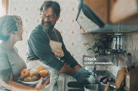 성숙한 부부 남자와 여자는 행복과 함께 집안일을 하고 결혼 생활이나 연애 생활을 즐기고 있습니다 부엌에서 설거지를 하는 남자와
