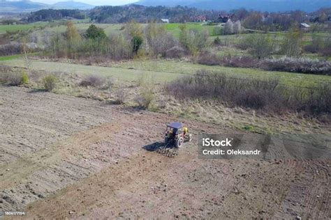 파종기가 달린 트랙터를 탄 농부가 마을 지역의 개인 밭에 있는 쟁기질한 땅에 곡식을 뿌립니다 봄 현장 작업의 기계화 농부의 일상
