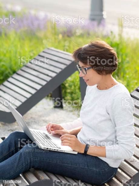 여자는 도시 공원 벤치에 노트북과 함께 앉아 직장에서 프리랜서 학생은 야외에서 원격으로 배운다 현대적인 라이프 스타일 Brand Name Online Messaging