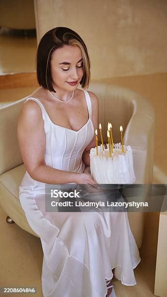 짧은 머리와 흰 드레스를 입은 귀여운 젊은 여자가 생일에 촛불이 달린 생일 케이크를 들고 있습니다 20 24세에 대한 스톡 사진 및 기타 이미지 Istock