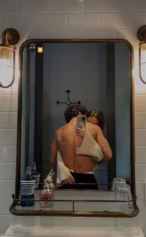 A Man And Woman Taking A Selfie In Front Of A Bathroom Mirror With