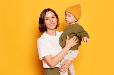 밝은 노란색 배경에 고립된 포즈를 취하는 귀여운 어린 아들과 함께 행복한 젊은 어머니 가족 사랑 모성 및 어머니의 날 개념 아들에 대한 스톡 사진 및 기타 이미지 Istock