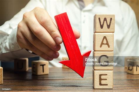 단어 임금과 빨간색 화살표 아래로 나무 블록 급여 감소 이익 하락 금융 위기 수준 내리기 낮은 이익 자본 유출 비즈니스 및 금융