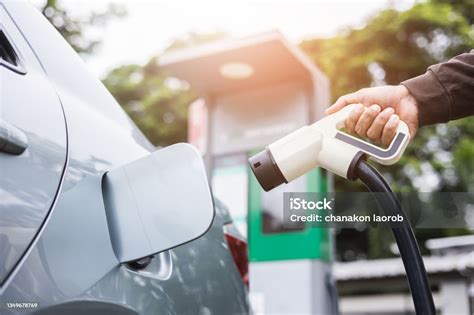 주차장에 Ev 자동차 전기 자동차 충전 전기 자동차 충전소에 연결된 남성 핸드 홀딩 전원 케이블 공급 장치 친환경 대체 에너지 미래 기술 배터리 차량 0명에 대한 스톡 사진