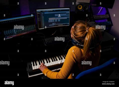 Female Music Producer Composing Music Using Computer Keyboard And Headphones In Professional